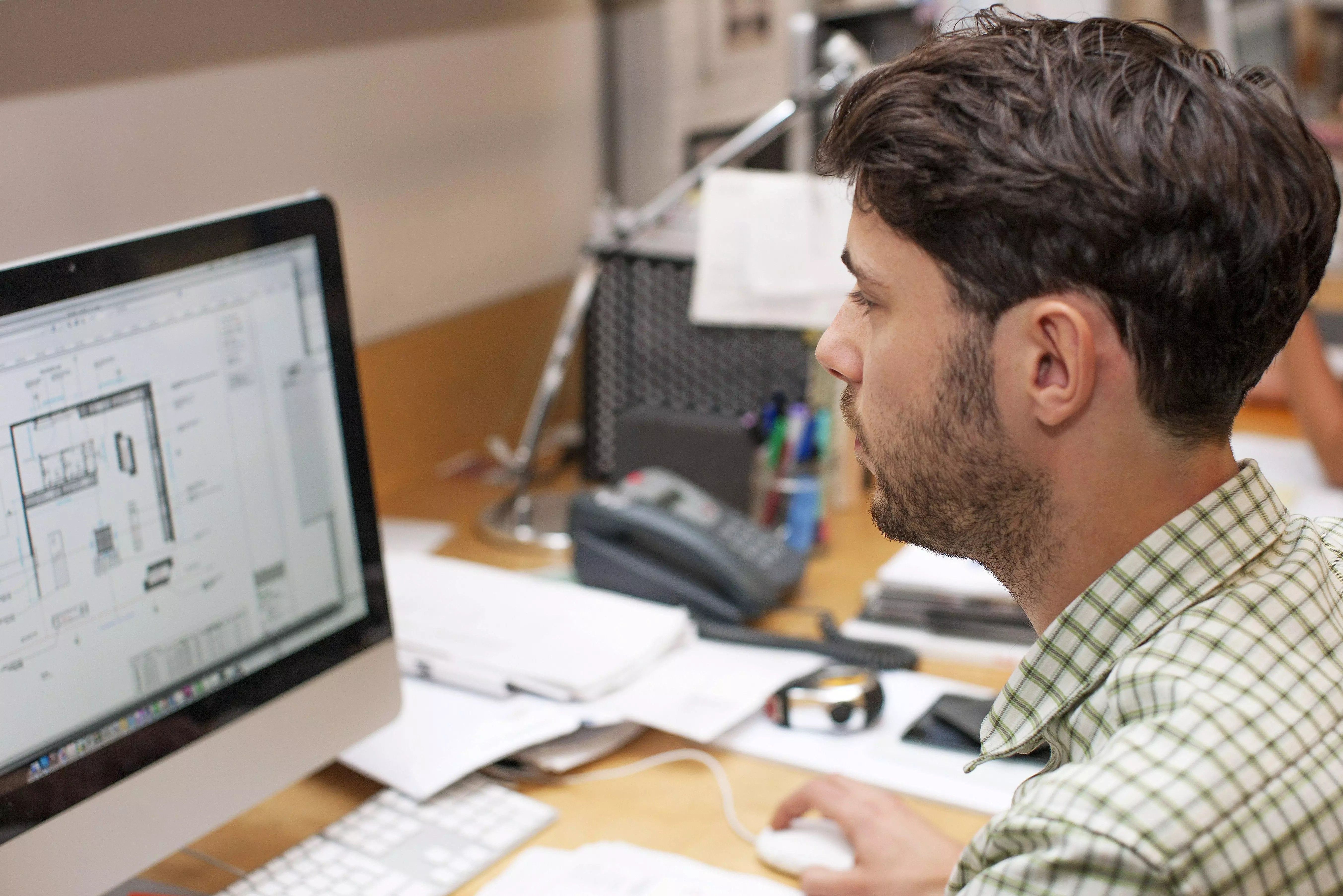 Arquitecto estudante de sexo masculino branco traballando nun plano nunha computadora