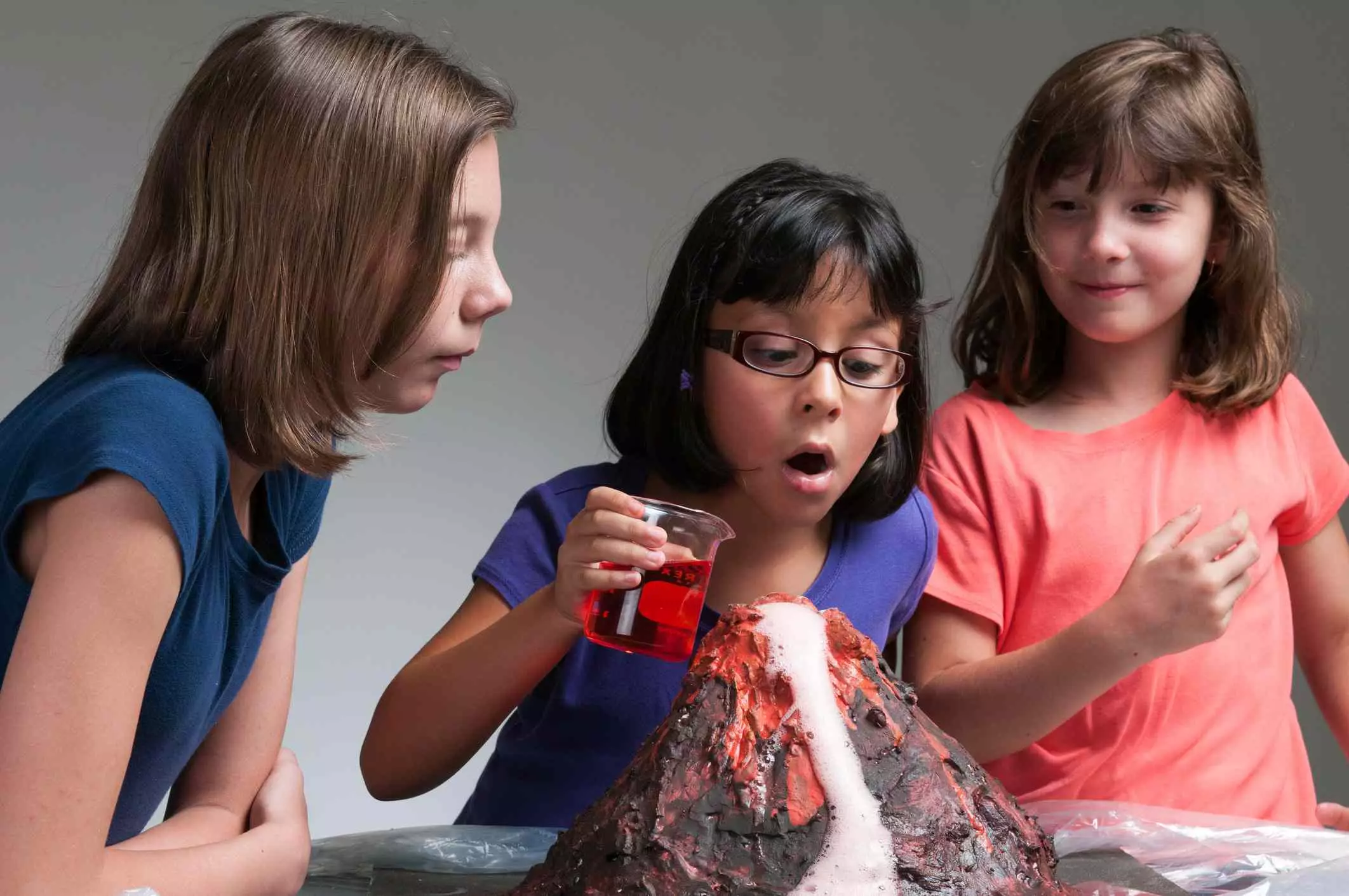 三個年輕的女學生觀看模型火山噴發。