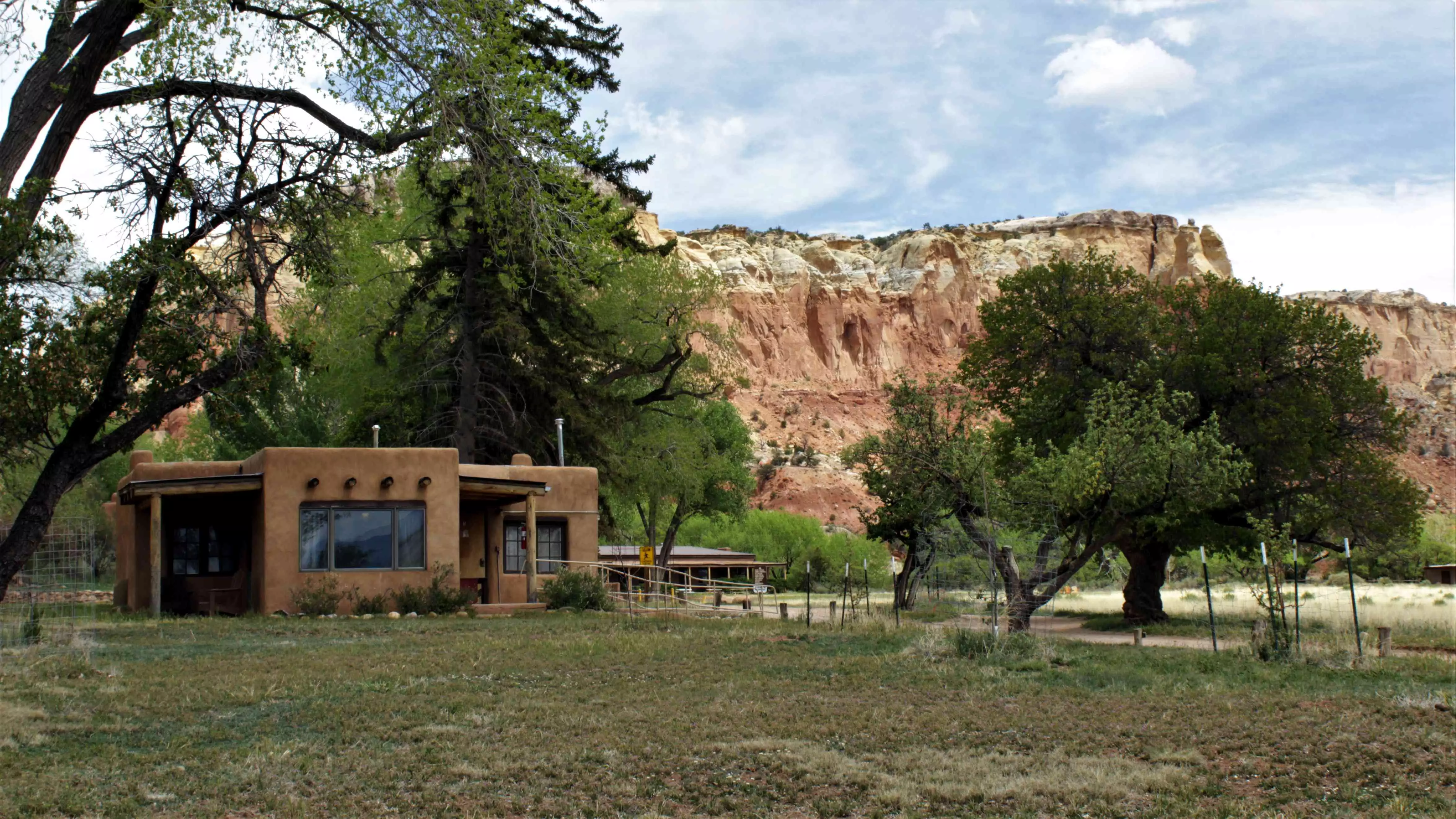 Pilt Georgia O'Keeffe'i kummitusrantšost Abiquius, New Mexico, ümbritsetud puude ja kõrbemaastikuga