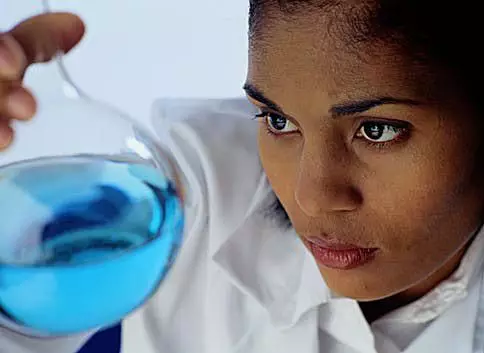 Chemicus die een fles vloeistof onderzoekt.