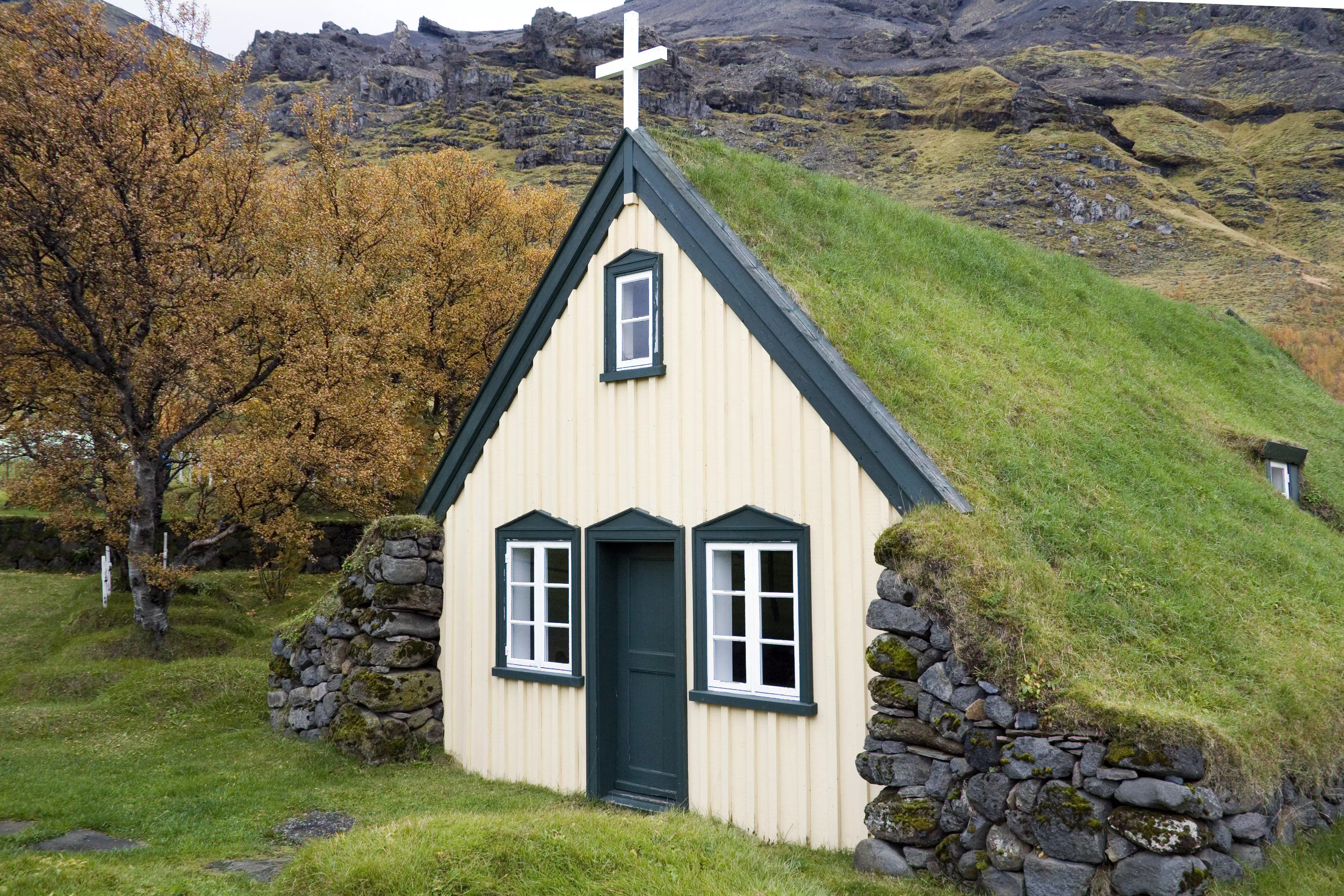 mała, biała fasada kościoła z dwuspadowym dachem z darni