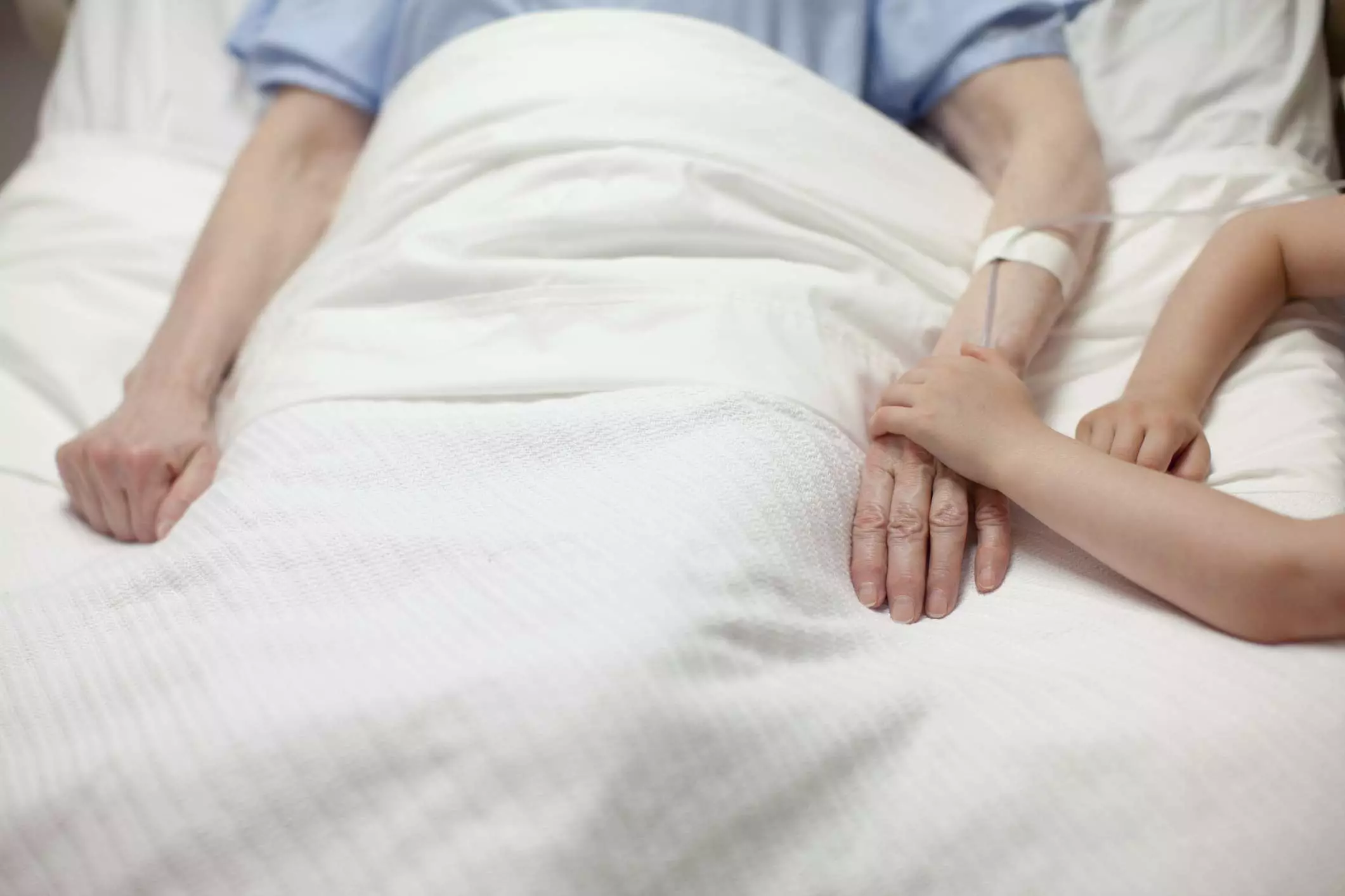 Gadis muda memegang tangan nenek di hospital
