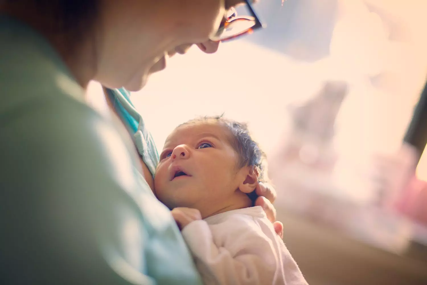 Neugeborenes Baby, das von einer lächelnden Frau gehalten wird.