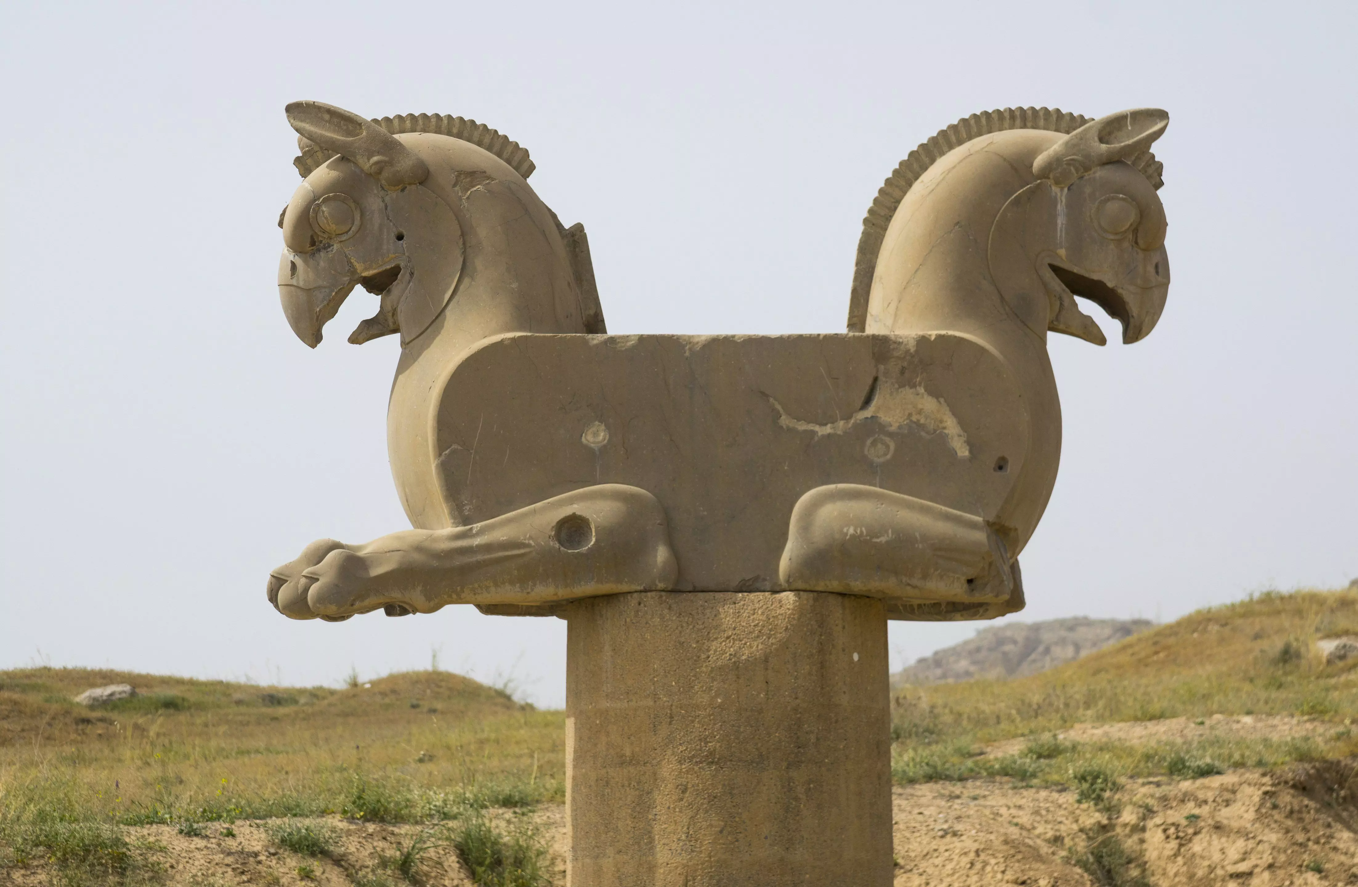 capitel de piedra reconstruida de dos cabezas de grifo apuntando hacia el otro lado