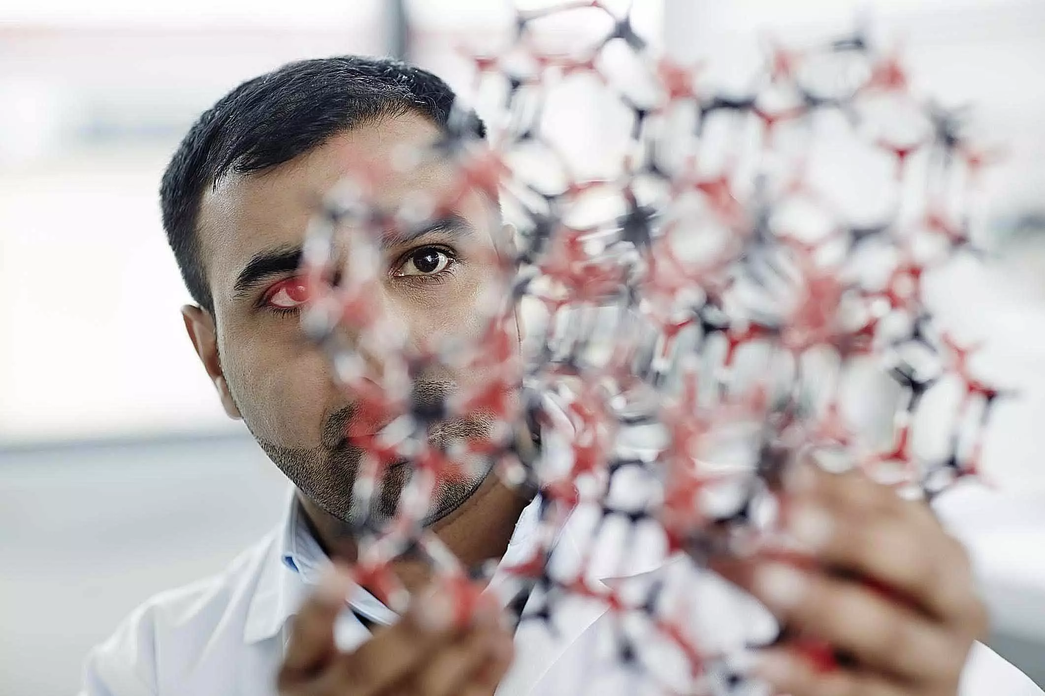 Njeriu që mban model plastik të molekulës së kimisë